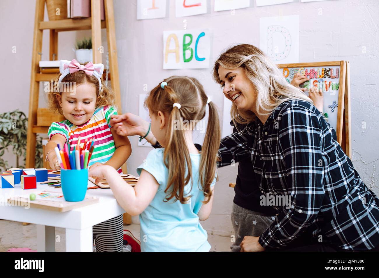 Des petites filles et une éducatrice qui étudient, jouent et plient des ...