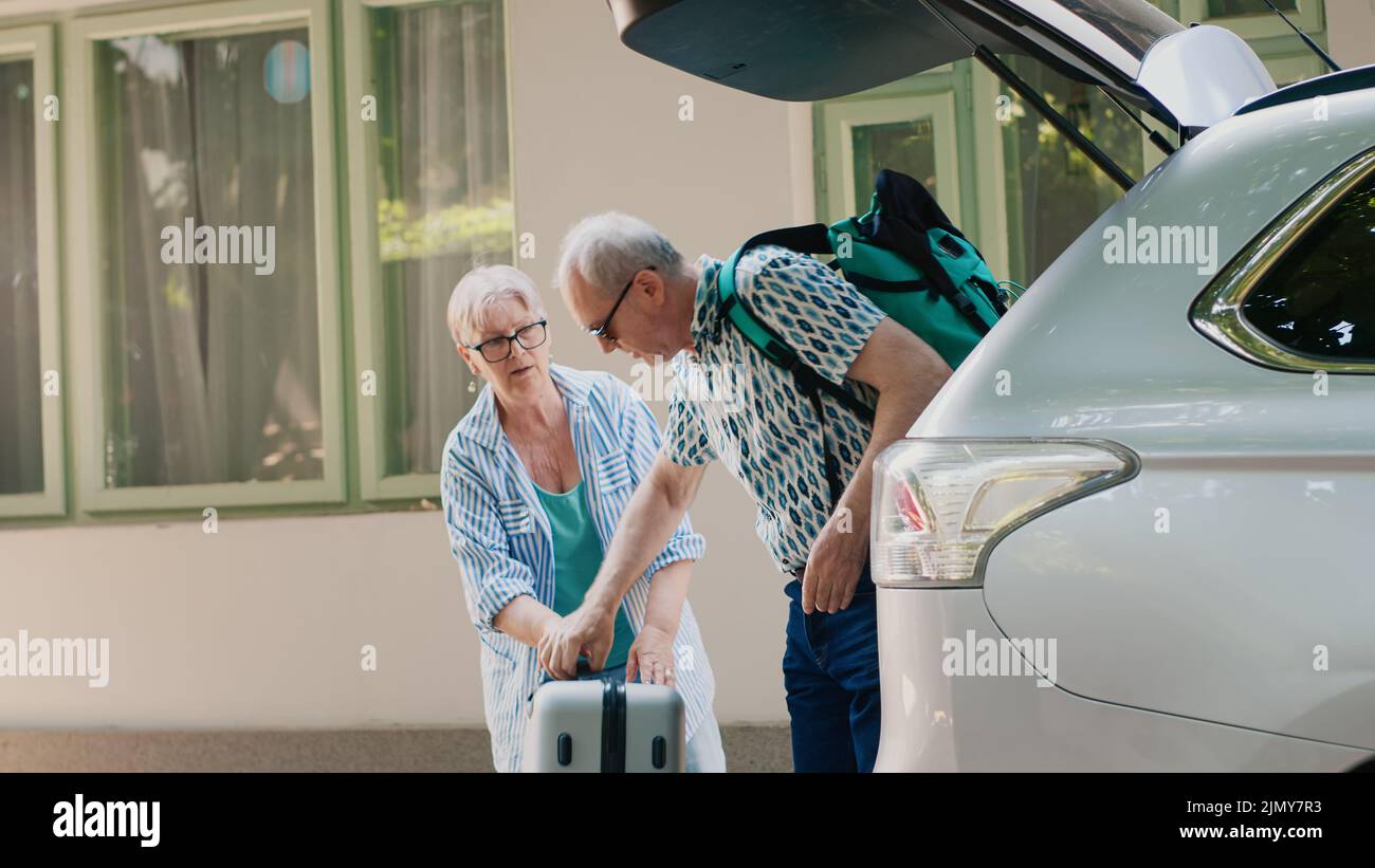 Les personnes âgées chargent leur véhicule avec leurs bagages et leurs ...