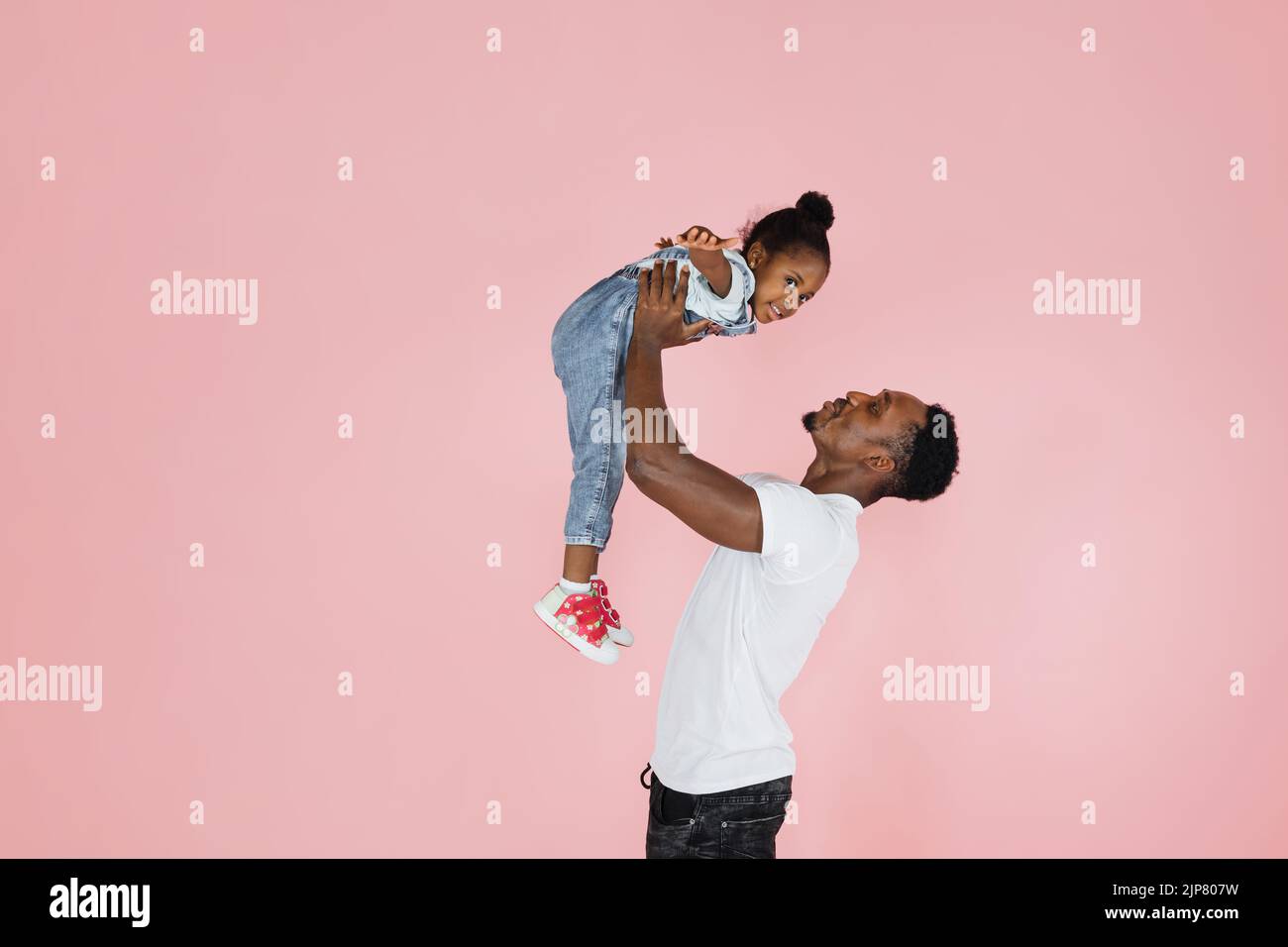 Bonne paternité. Joyeux papa africain tenant sa jolie fille sur les mains prétendant qu'elle ...
