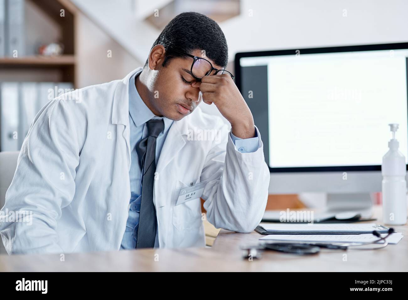 Un jeune homme stressé et fatigué médecin à son bureau dans un hôpital ...