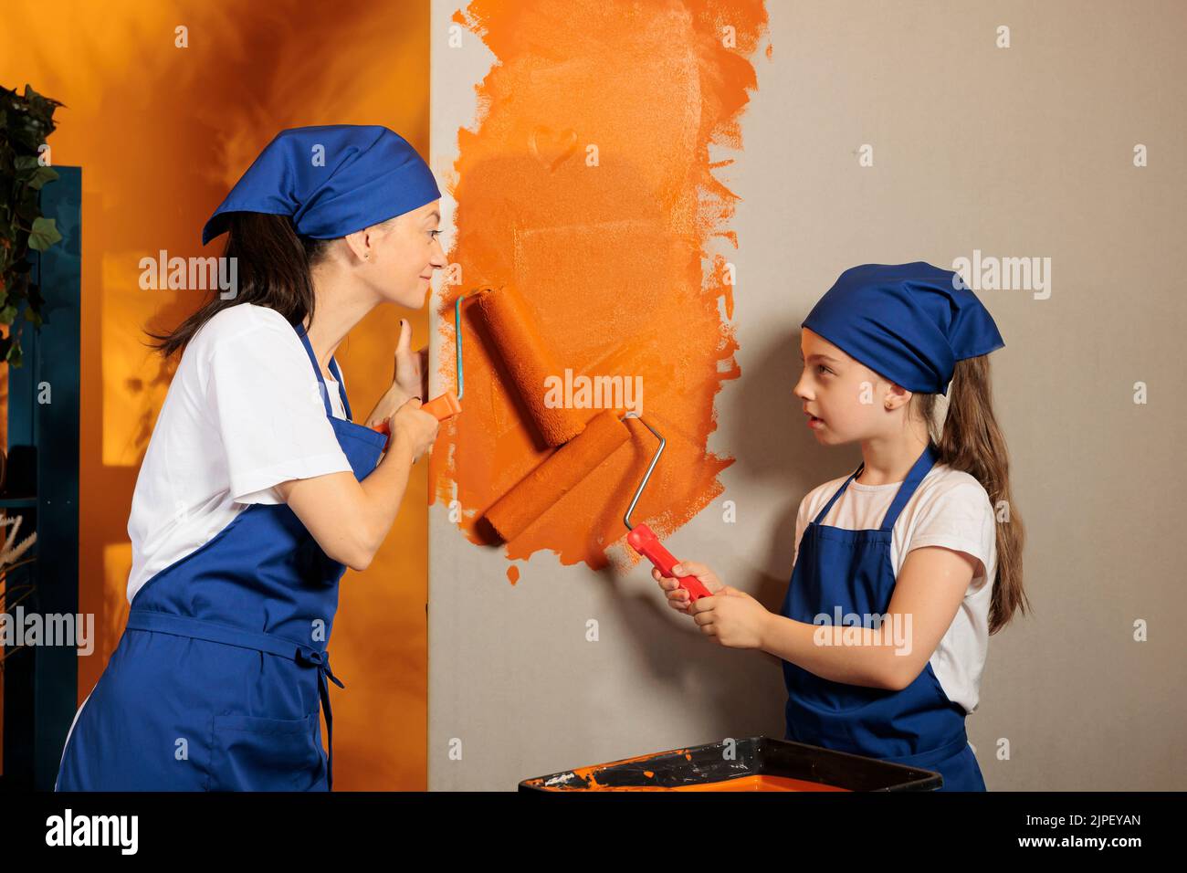 Maman et fille utilisant de la peinture orange sur les murs de la ... Maman et fille utilisant de la peinture orange sur les murs de la ...