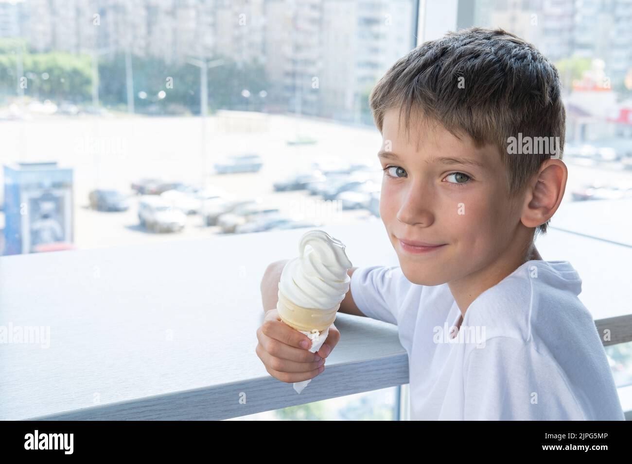 Un jeune garçon mignon mange une glace blanche tourbillonnante dans une ...