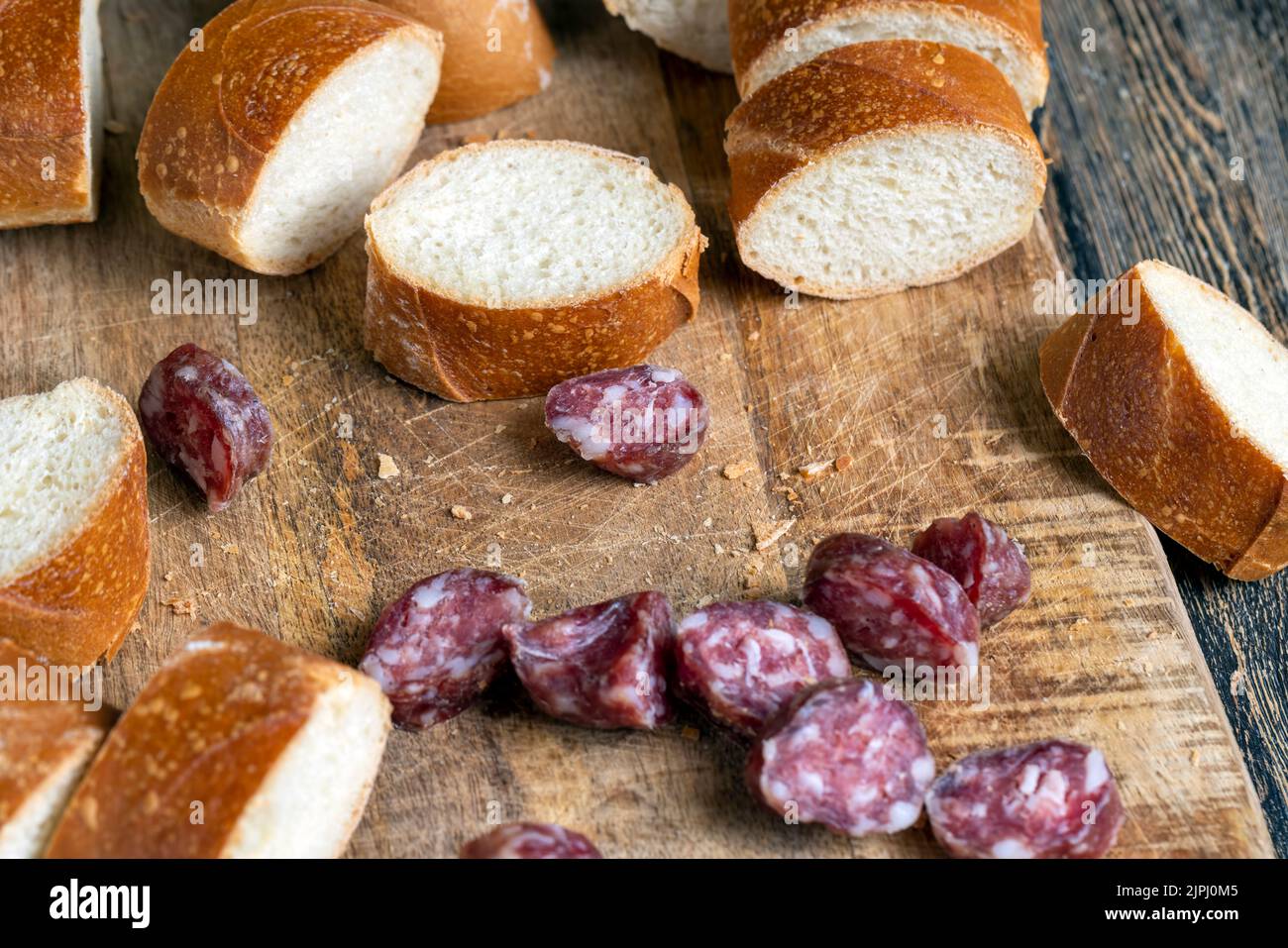saucisse tranché avec une baguette sur une planche à bois, saucisse de porc maison tranché avec ...