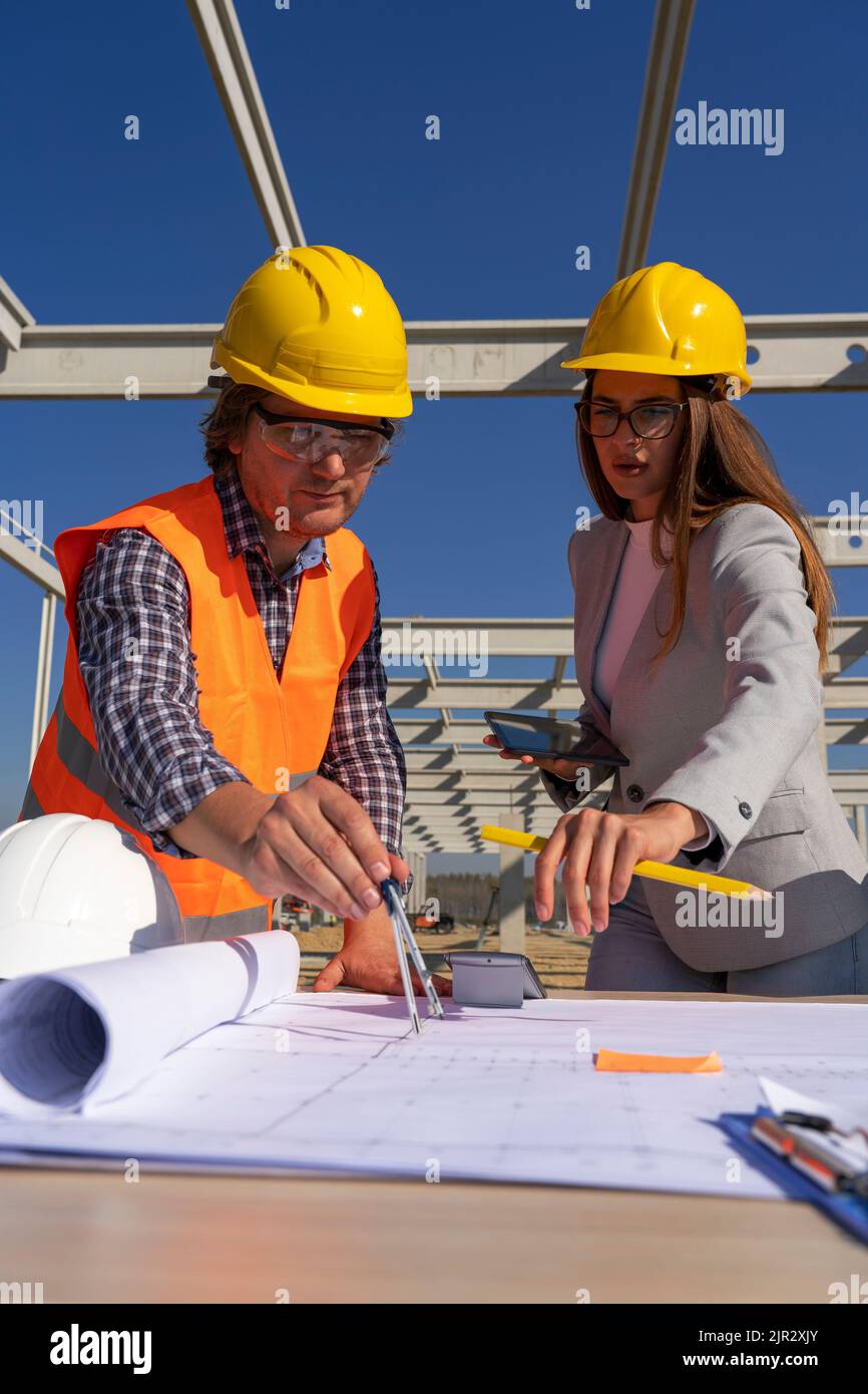Jeune femme architecte et superviseur de la construction Vérification du plan directeur de la ...