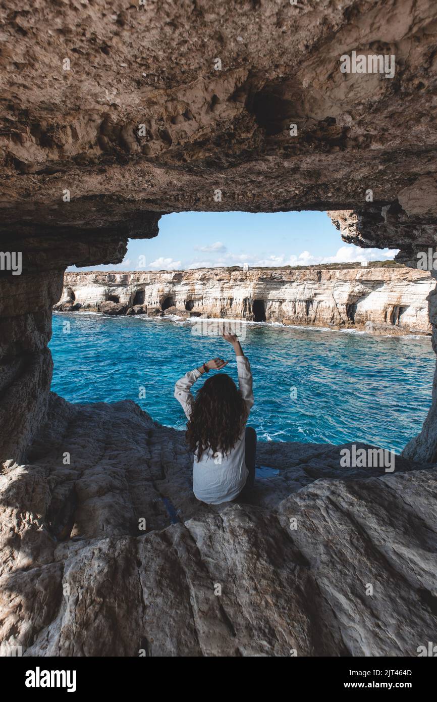 Une jeune femme de derrière est assise dans un trou de grotte et ...