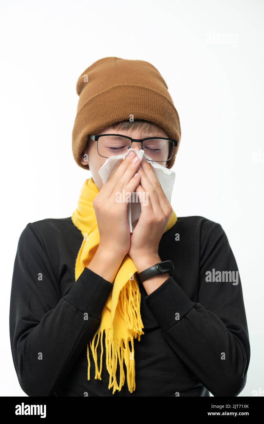 Le garçon enveloppé d'un foulard a un nez qui coule et souffle son nez ...