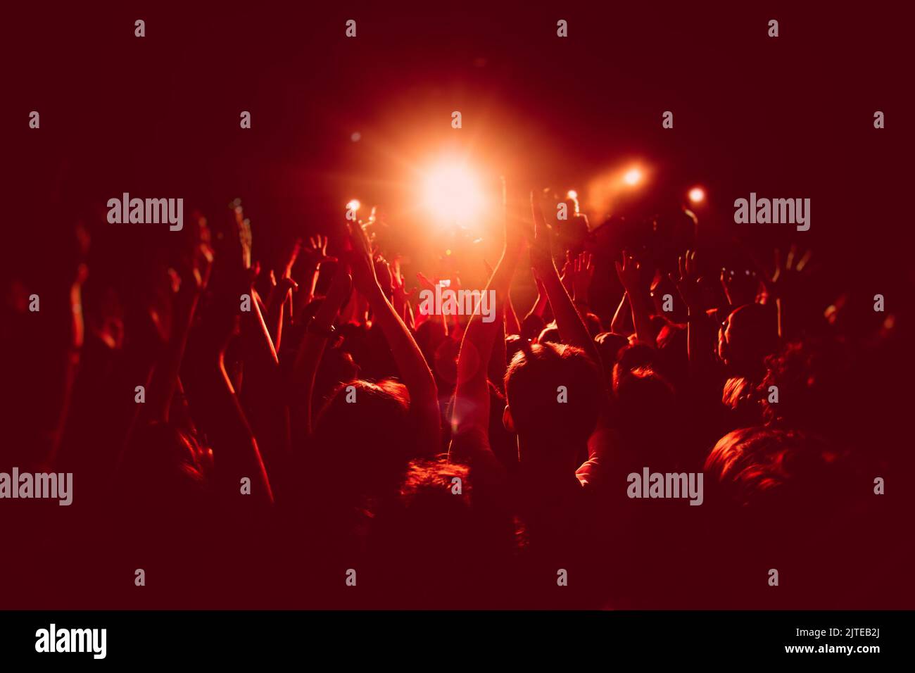 Une salle de concert bondée avec scène dans des lumières rouges ...