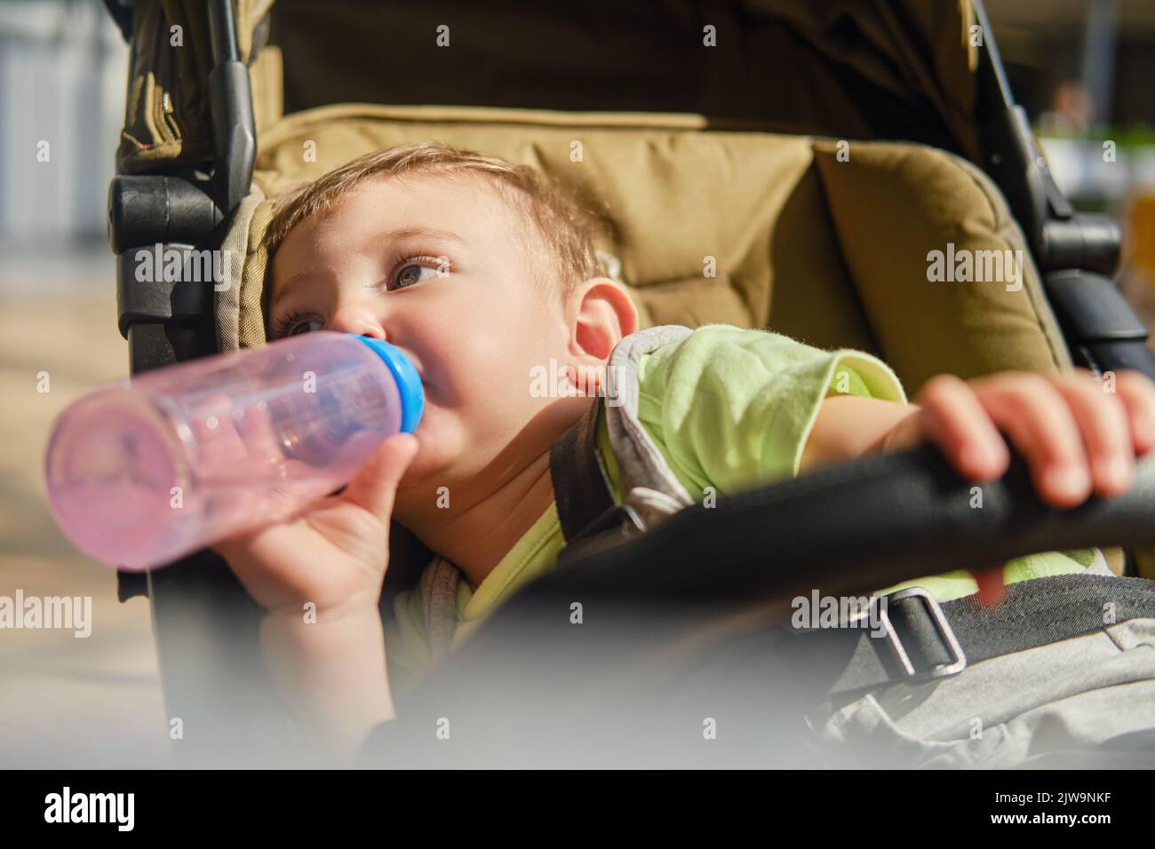 Un petit garçon heureux qui boit de la préparation pour bébé à partir d ...
