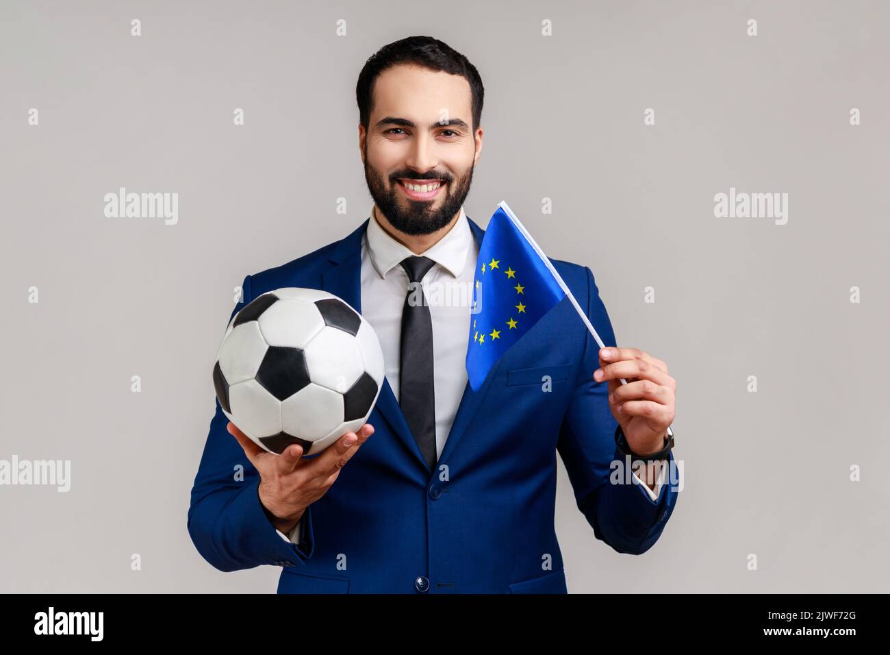 Joyeux homme à barbe, portant un ballon de football noir et blanc et le ...