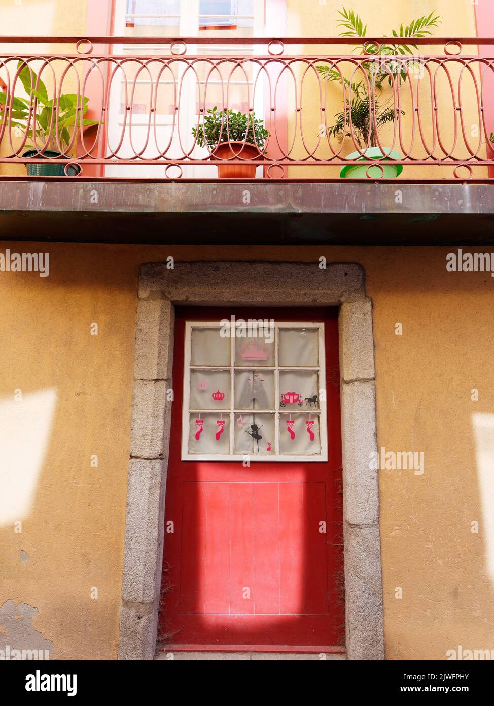 Maison colorée avec une porte rouge et un balcon à Porto avec des pots ...
