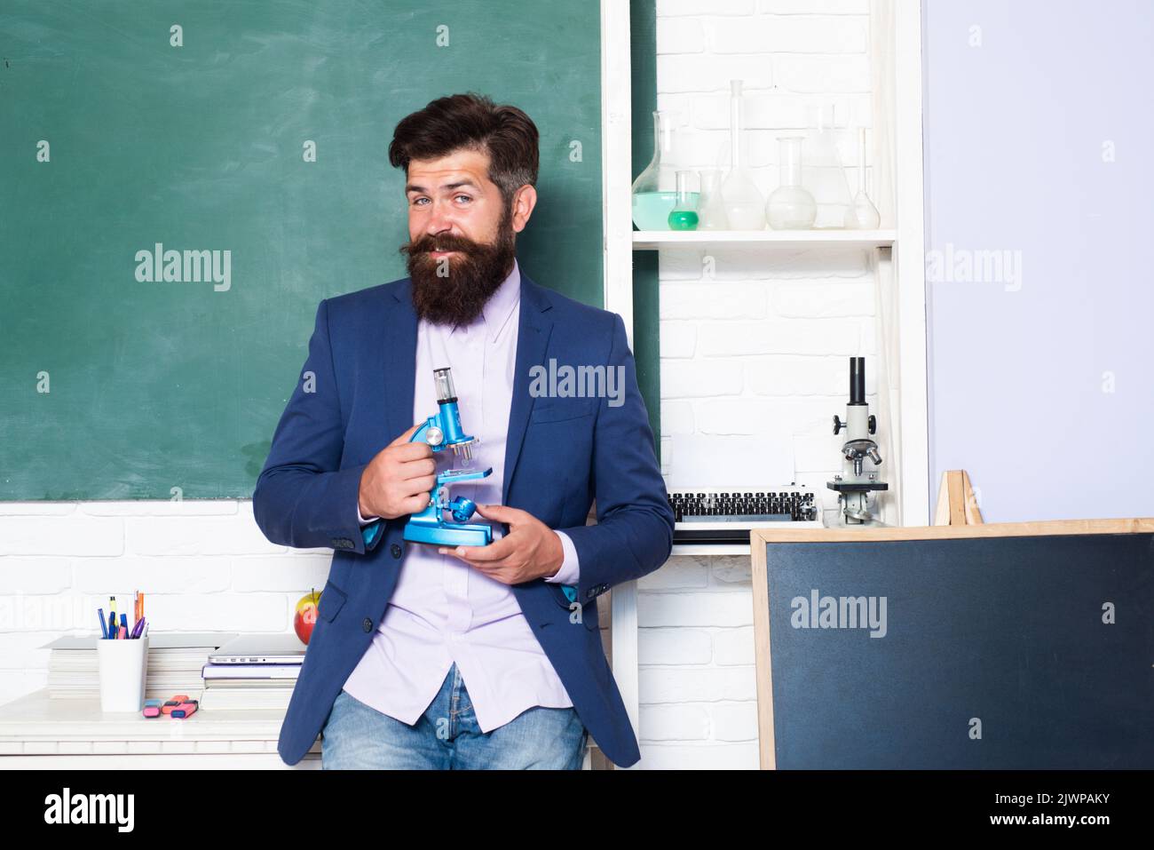 Portrait de l'homme enseignant tient le microscope à l'école en classe ...