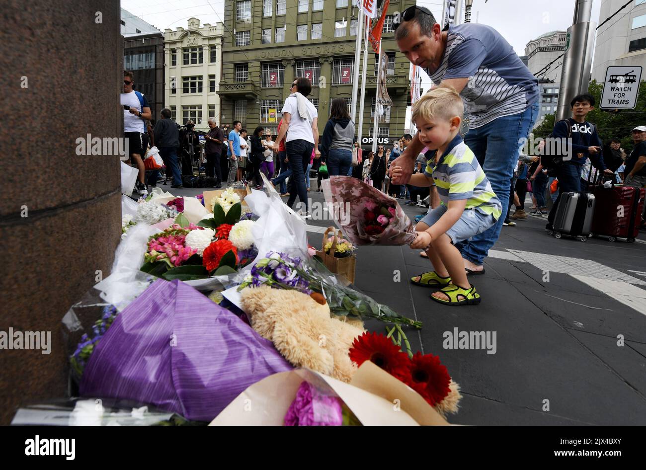 Un enfant pose des fleurs au coin de la rue Bourke et Elizabeth après ...