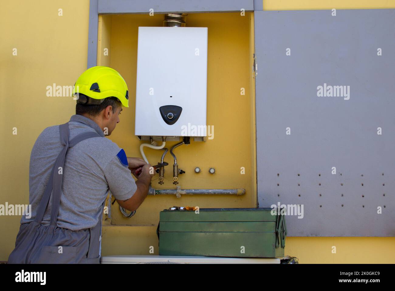 Plomber sur une échelle avec une clé lors de la réparation et de l'entretien d'une chaudière à ...