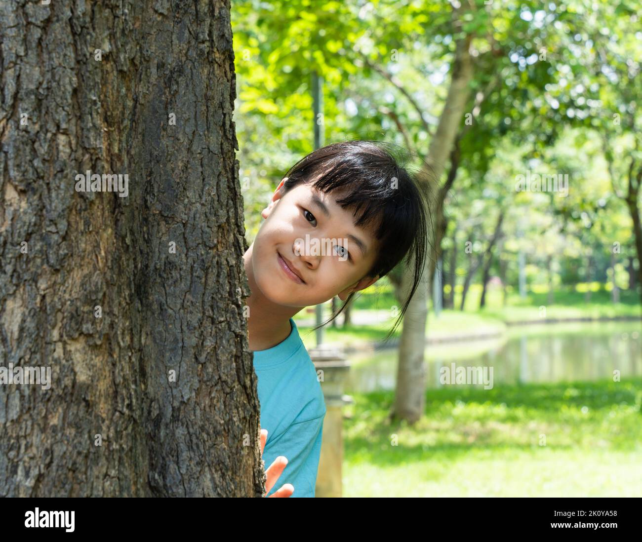 Une jolie petite fille qui se cache derrière un arbre. Portrait de l ...