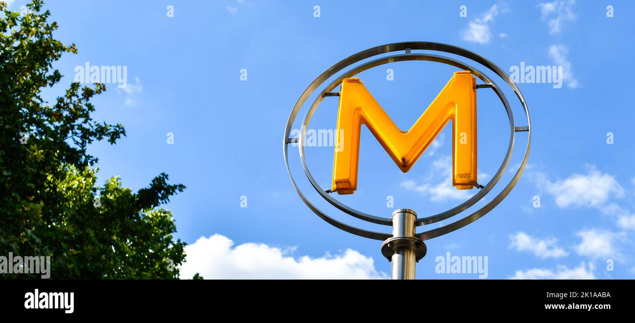 L'illustration montre un panneau avec le logo du métro (symbole jaune ...
