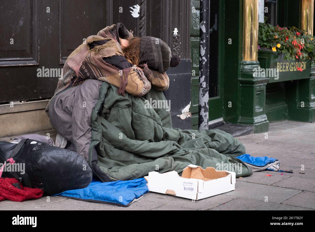 L'homme ou le bum sans-abri, enveloppé dans des couvertures et des sacs ...