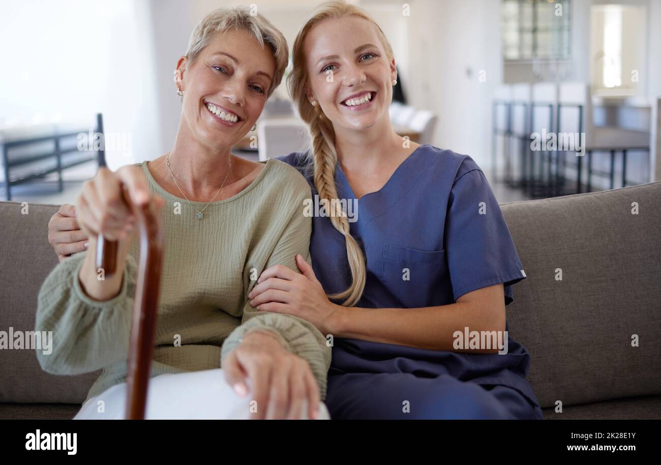 Portrait de l'infirmière et de la femme âgée avec canne sur le canapé ...