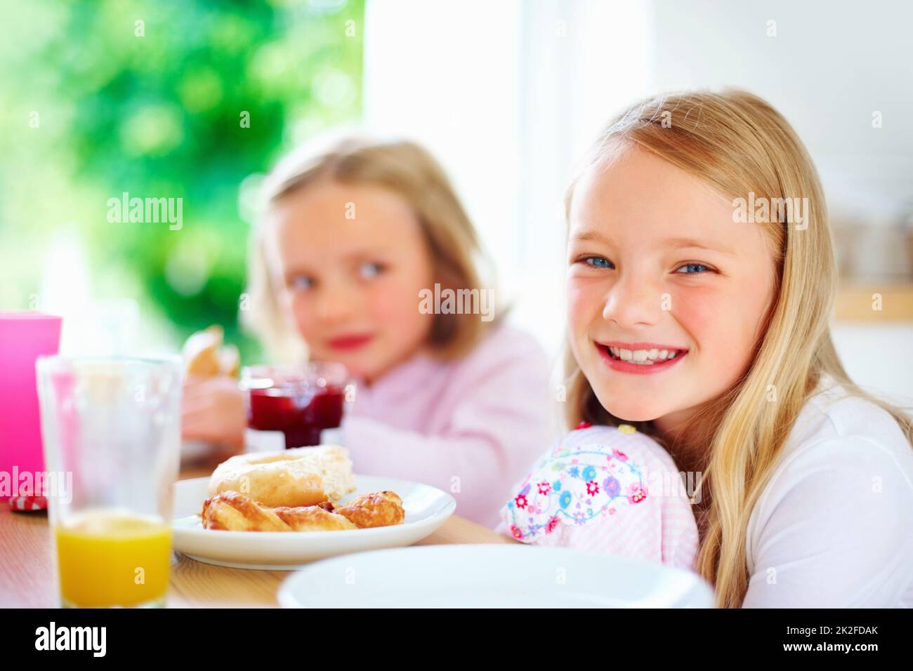 Petite fille souriante avec sa sœur prenant le petit déjeuner. Portrait ...