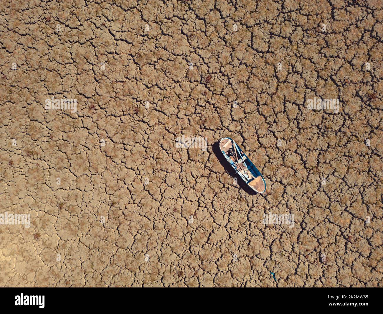 Bateau à rames abandonné sur un sol fissuré sur un lit de lac séché en ...