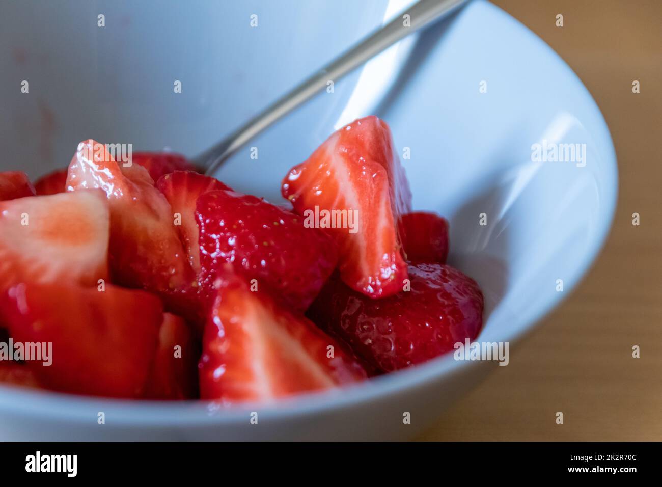 De nombreuses fraises coupées dans un bol sont prêtes à manger avec une ...