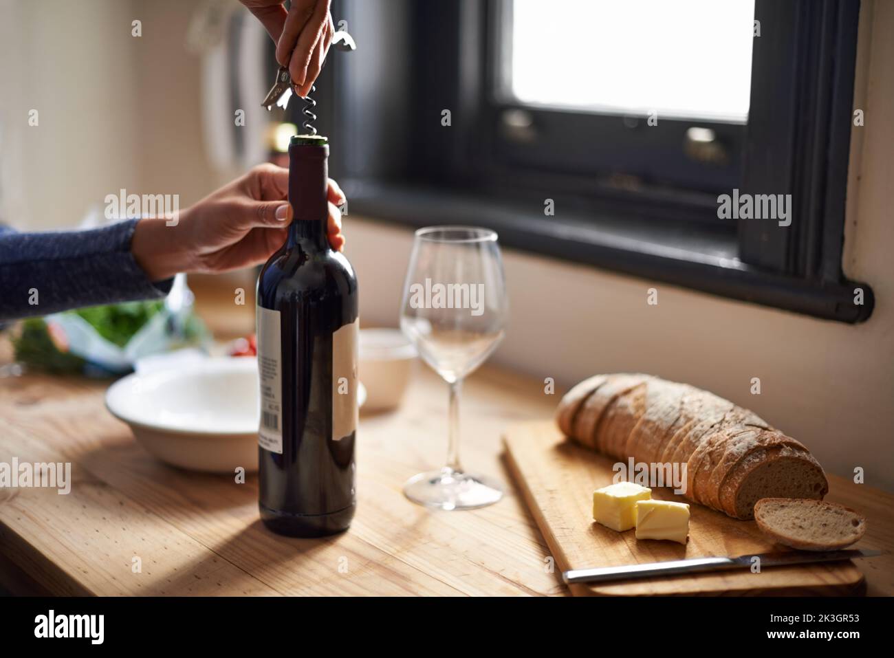 Me verser un peu de vin. Une jeune femme ouvre une bouteille de vin ...