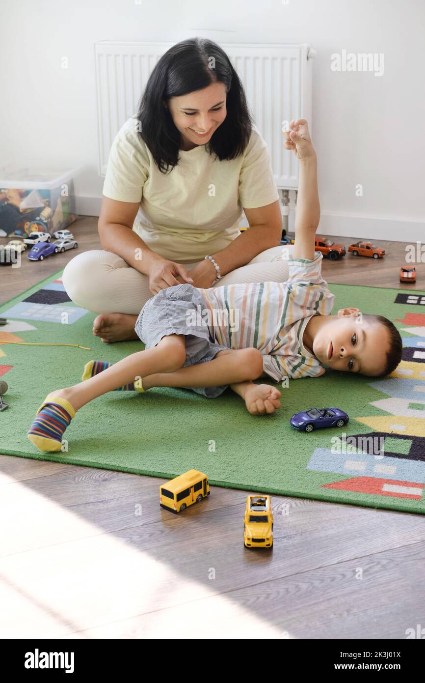 Garçon handicapé jouant des voitures jouets avec la mère à la maison ...