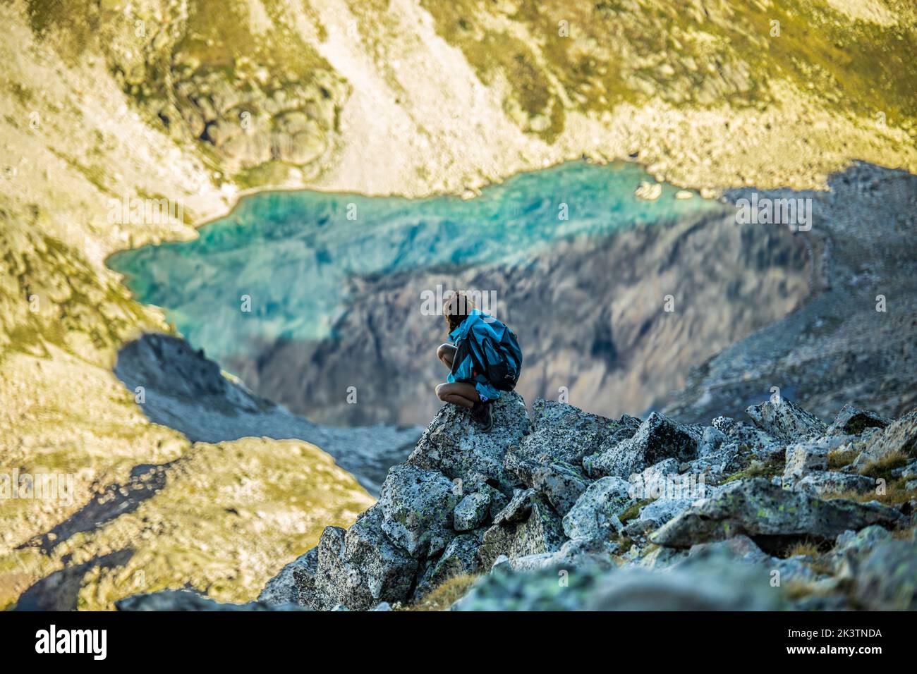 Vue latérale d'un alpiniste méconnu avec sac à dos assis sur le rocher ...