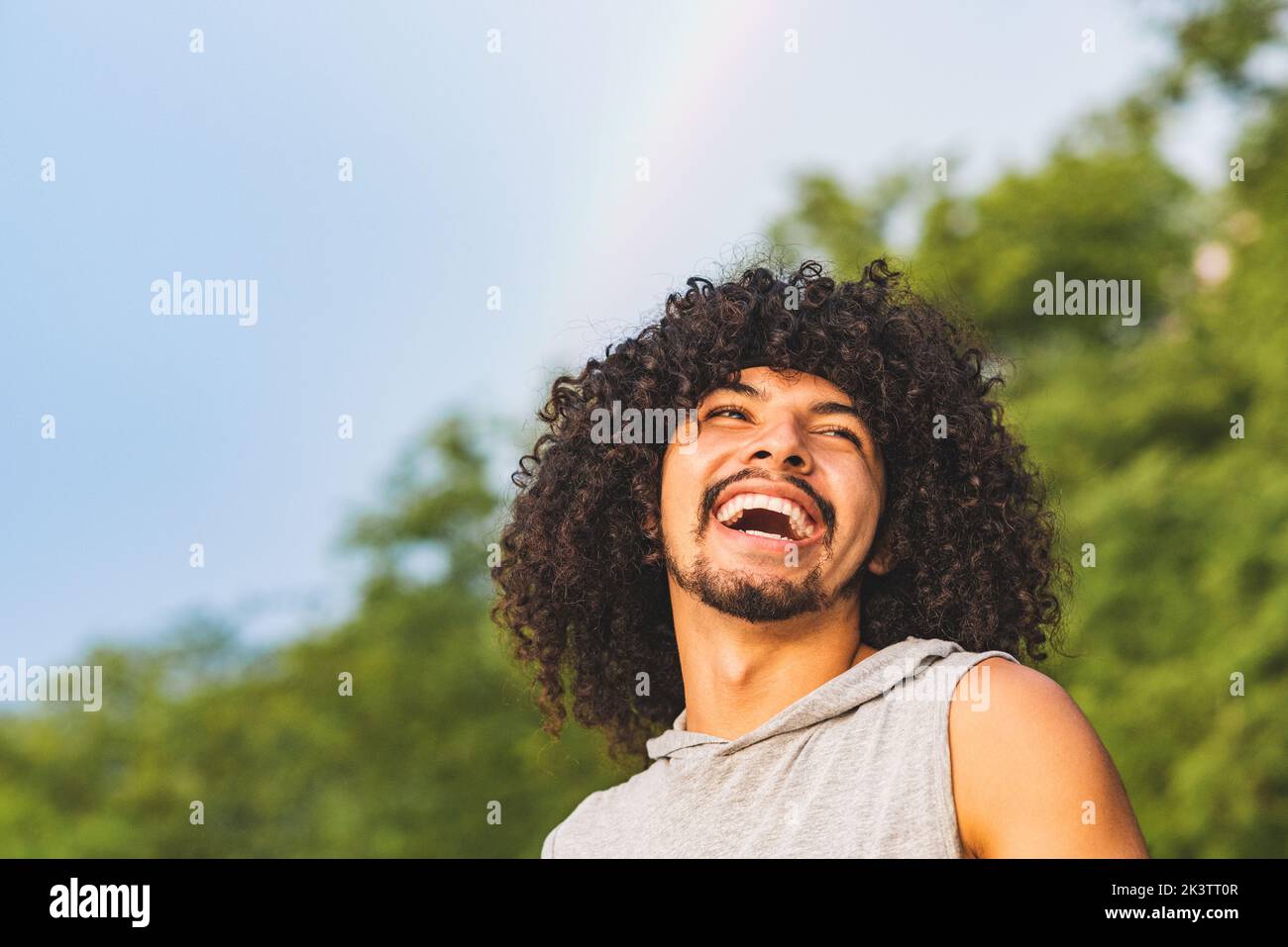 Petit angle de rire jeune latino-américain barbu avec de longs cheveux ...