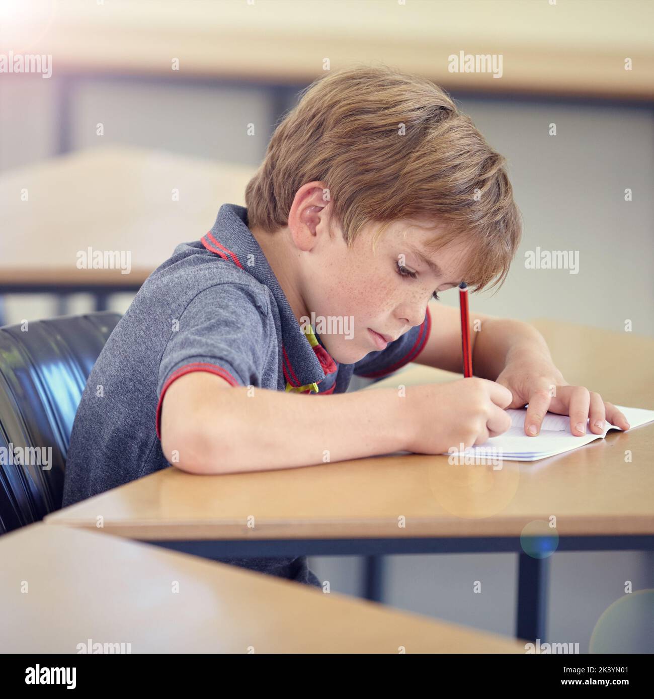 Se concentrer sur son travail de classe. Un petit garçon faisant son ...