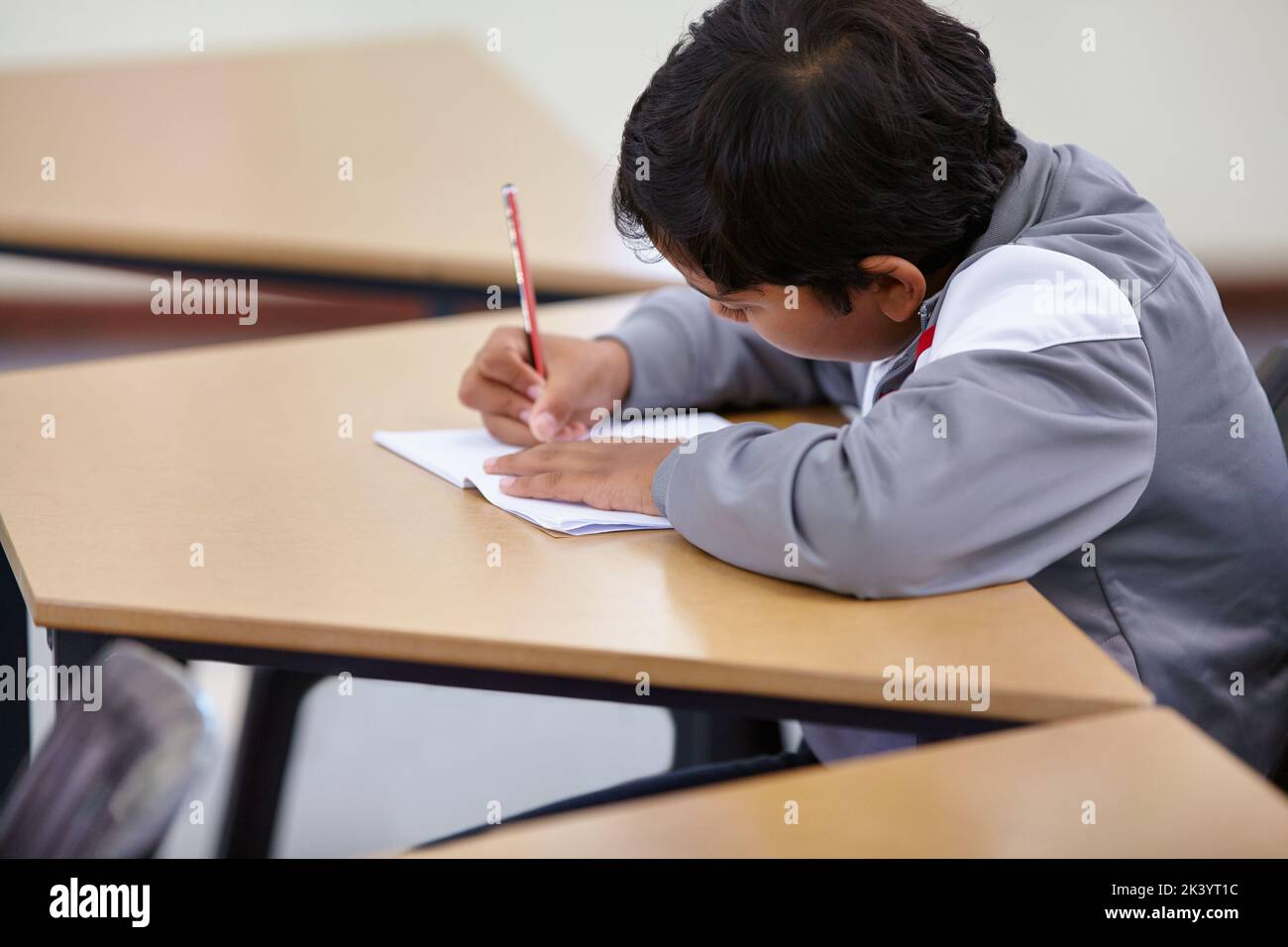 Travailler dur à l'école. Un jeune élève écrit dans un cahier d ...