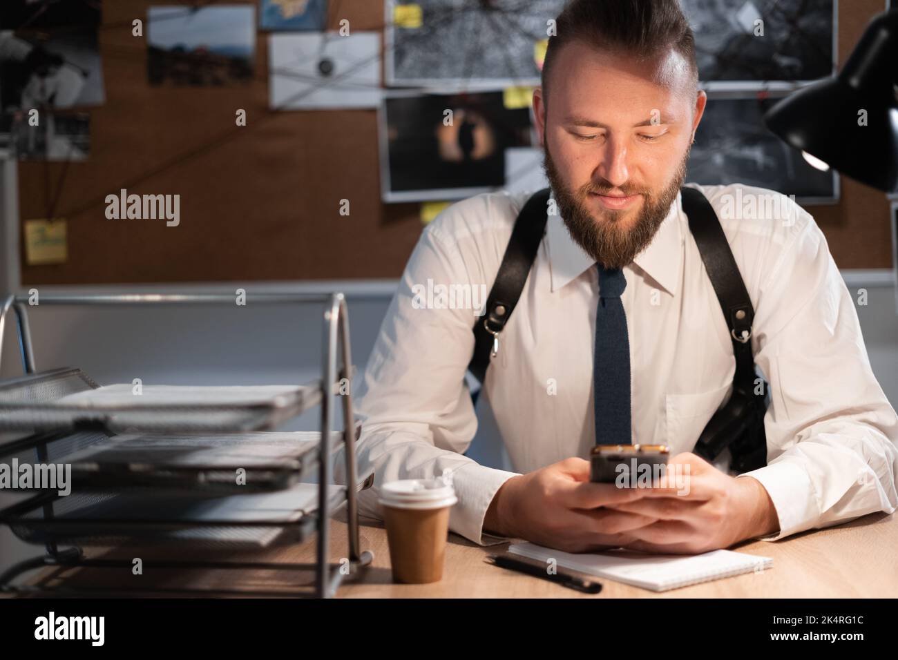 Un détective masculin est assis dans le bureau en feuilletant le fil d ...