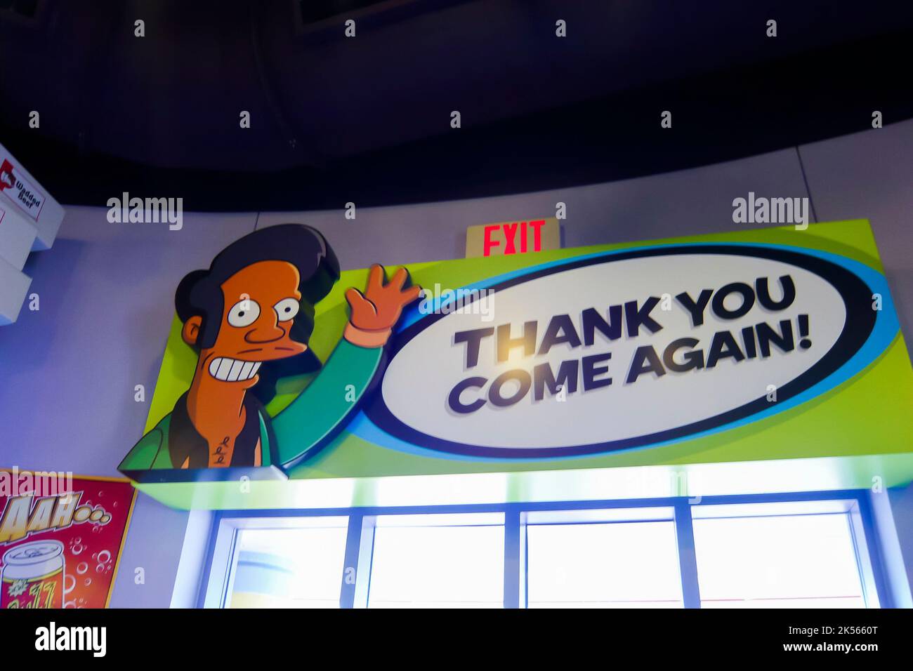 Panneau au-dessus de la sortie d'un Kwik-e-Mart avec APU disant "Merci ...