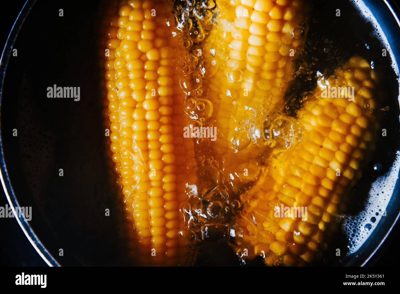 Le maïs juteux orange est bouilli dans de l'eau avec du sel. Maïs dans ...