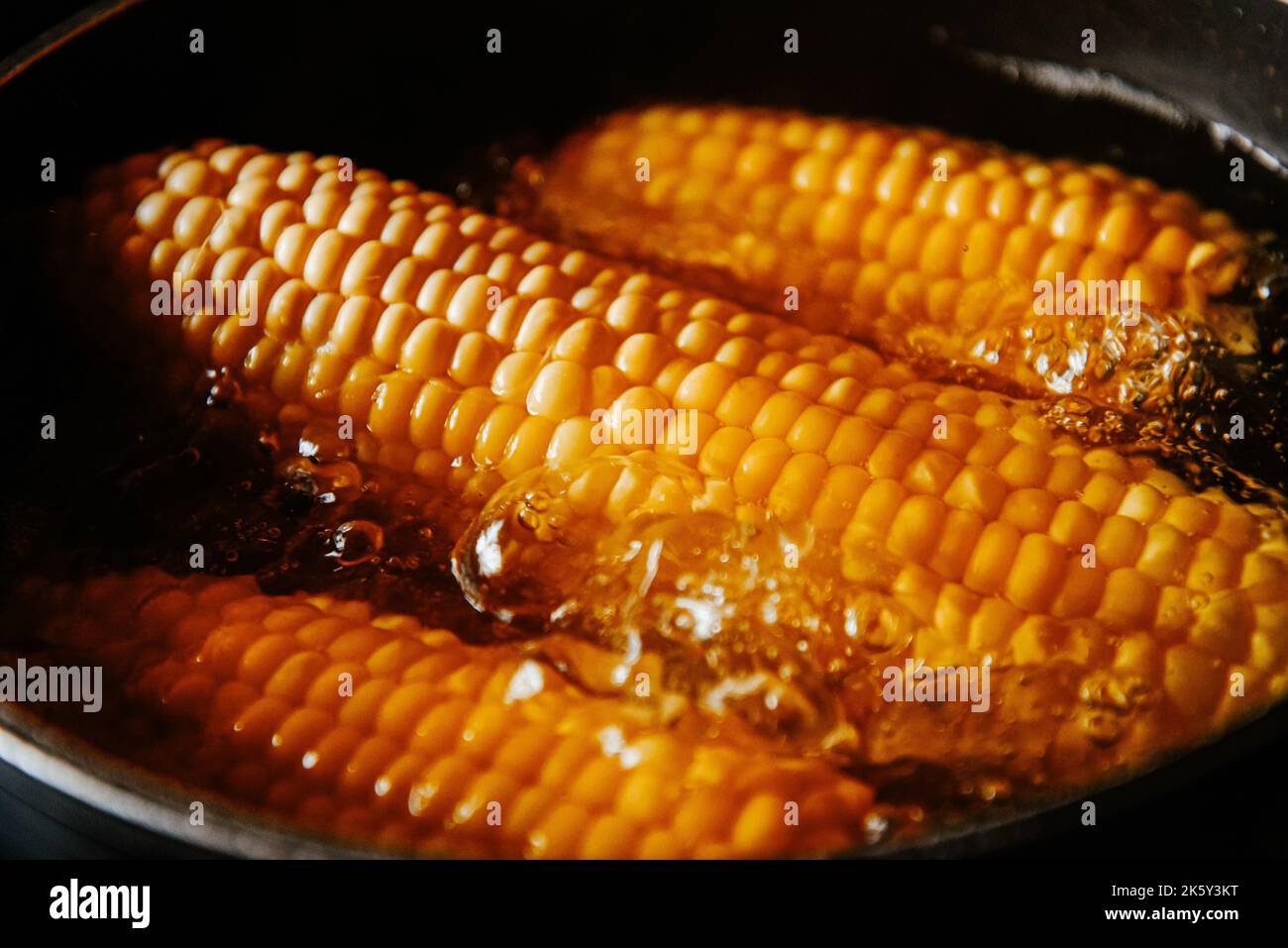 Le maïs juteux orange est bouilli dans de l'eau avec du sel. Maïs dans ...