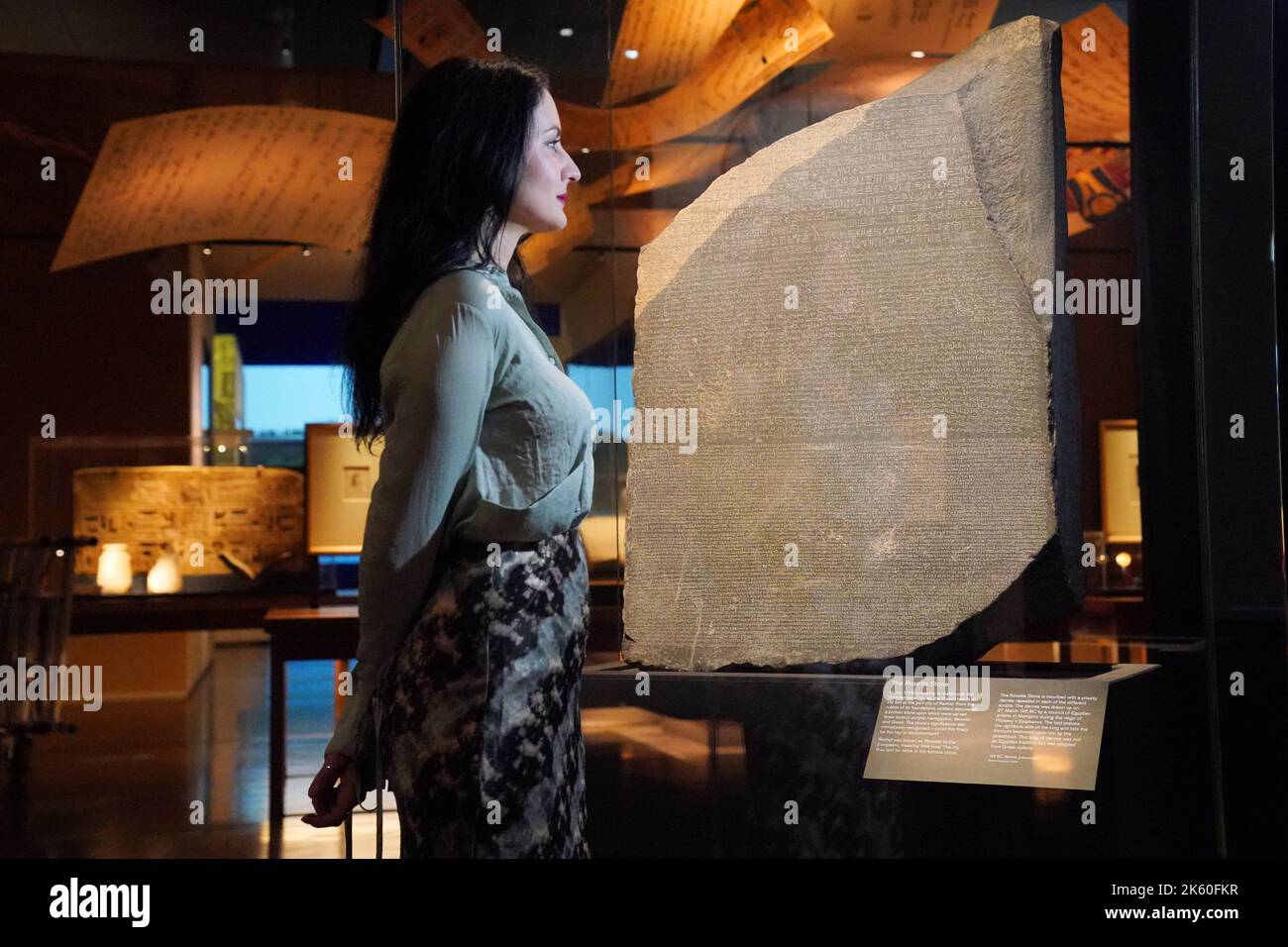 Un membre du personnel observe la pierre de Rosetta exposée lors de l'exposition hiéroglyphes ...