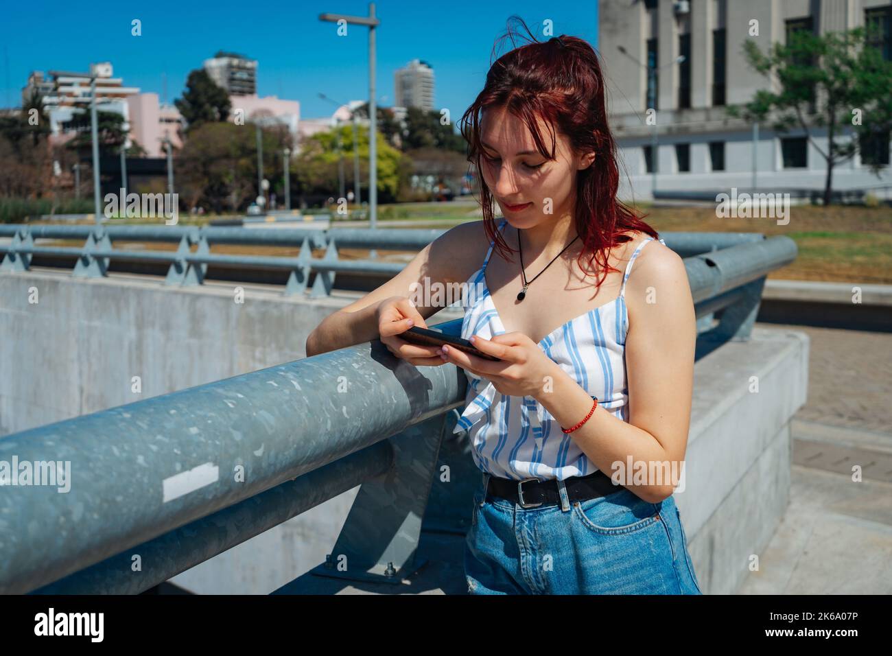 Une jeune femme à tête rouge qui vérifie les messages sur son téléphone ...