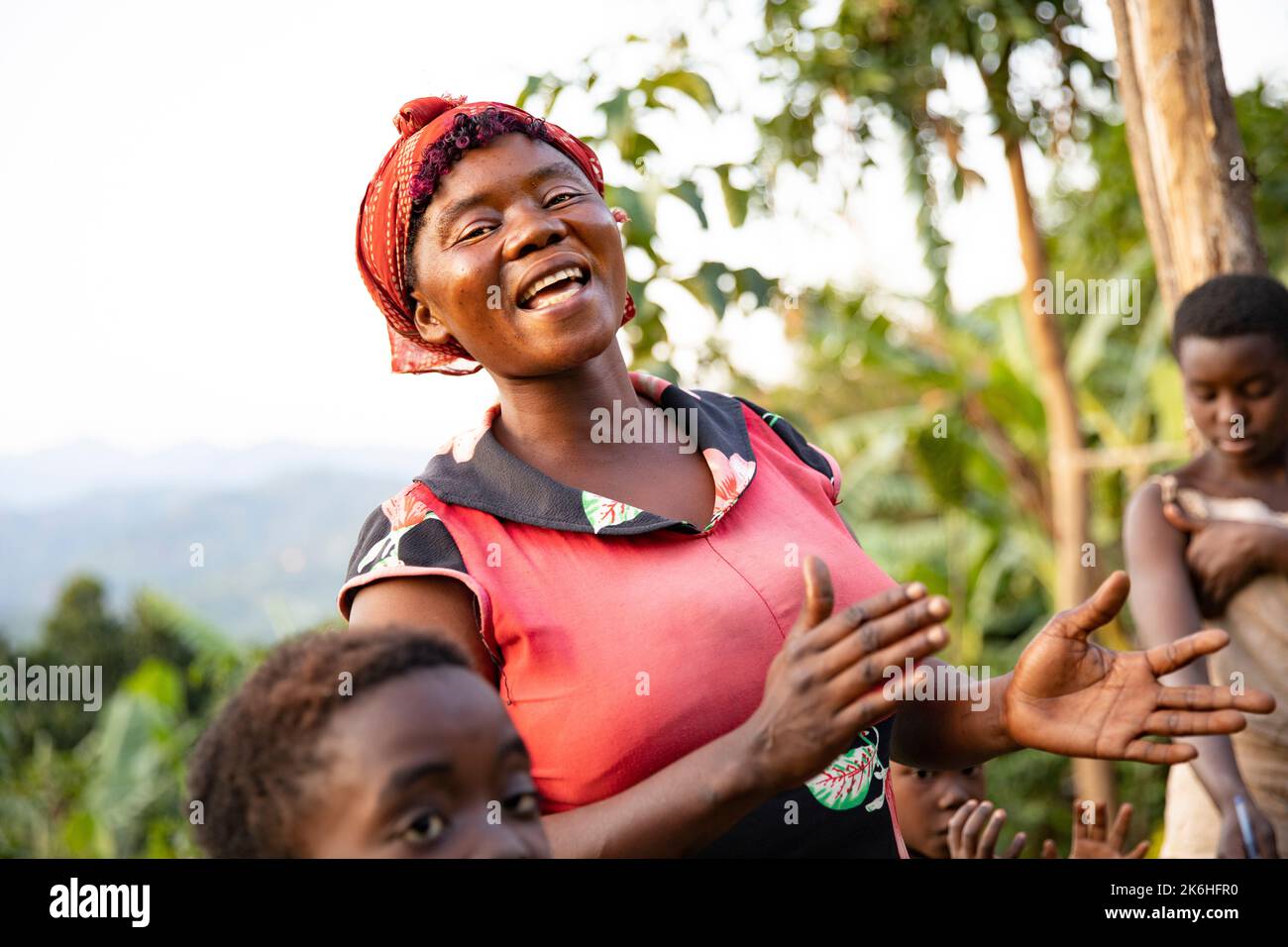 Une femme africaine heureuse chante avec sa famille devant chez elle ...