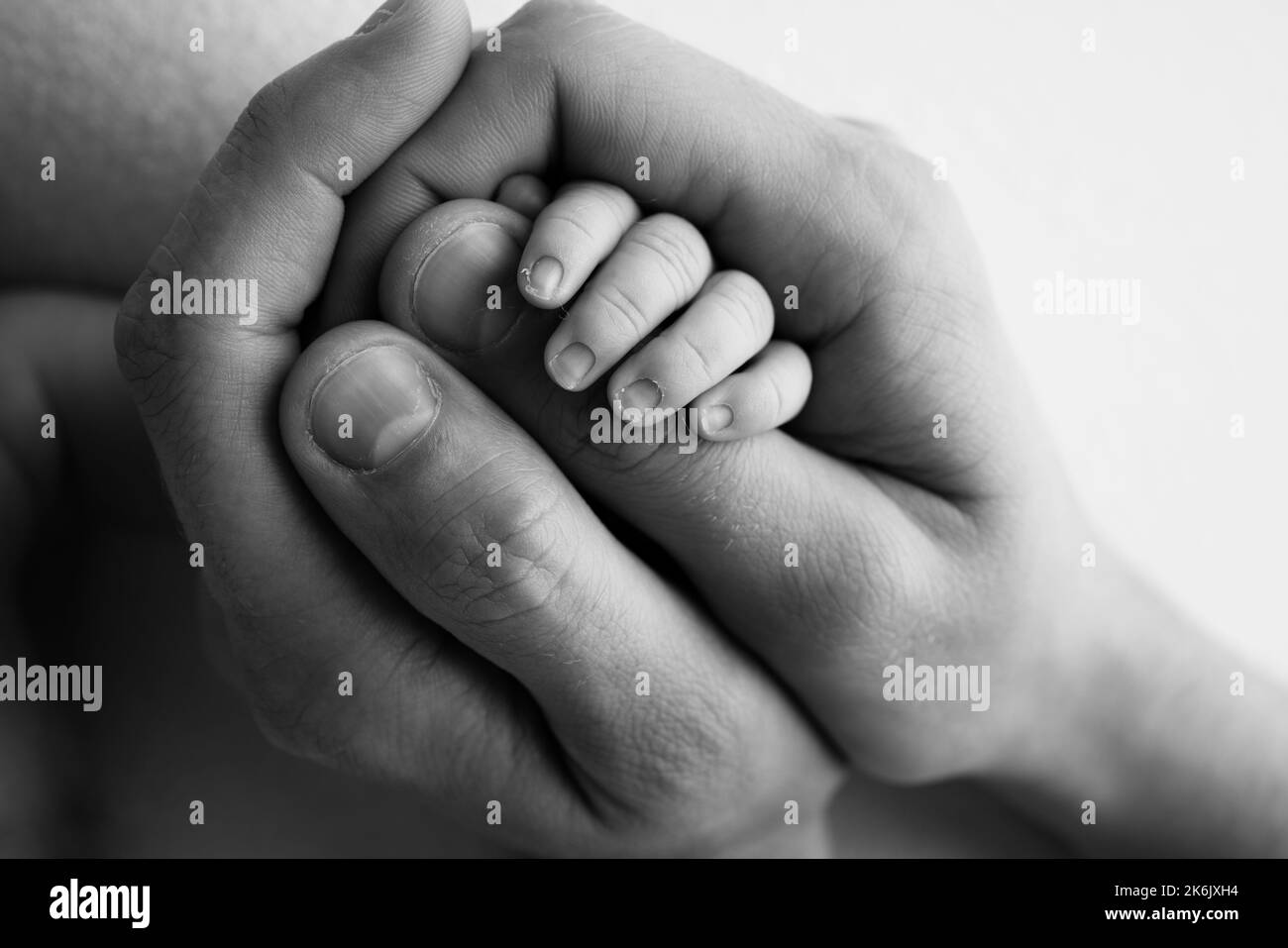 Un nouveau-né tient le doigt de sa mère, de son père. Les mains des ...