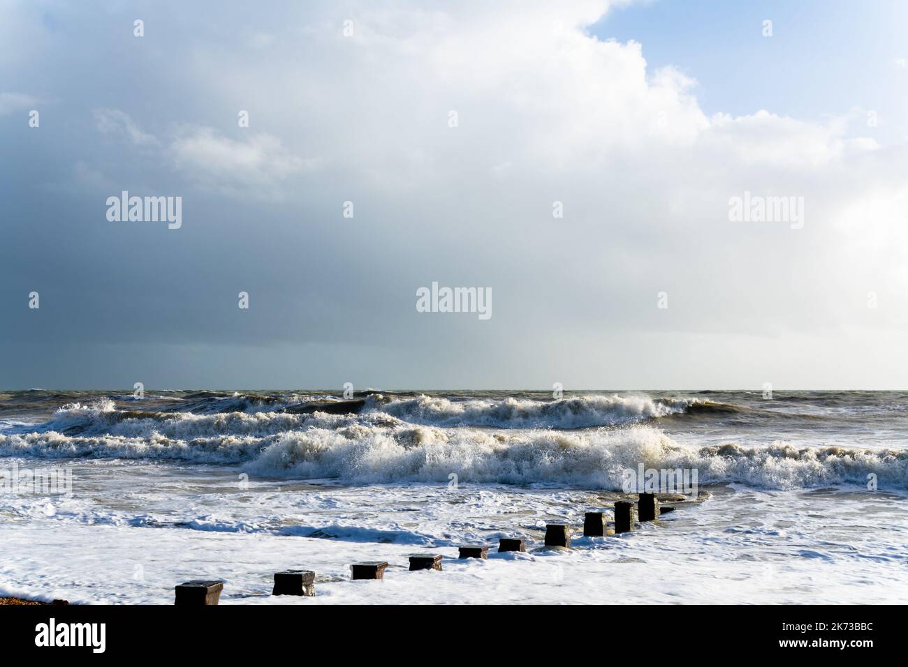 Vagues se brisant sur la plage à Bexhill-on-Sea avec des nuages de ...