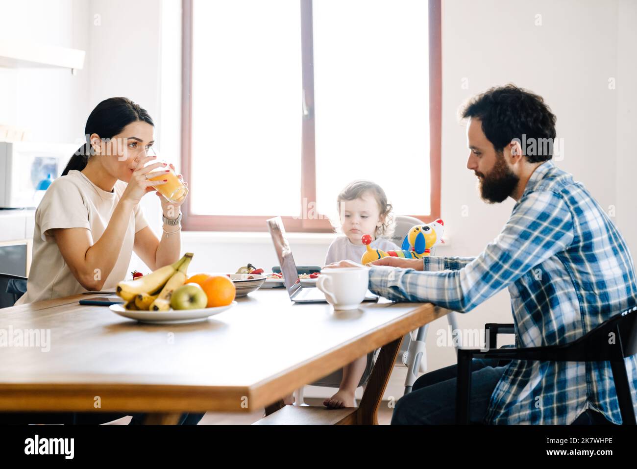 Une jeune famille heureuse avec un petit fils prenant le petit déjeuner ...