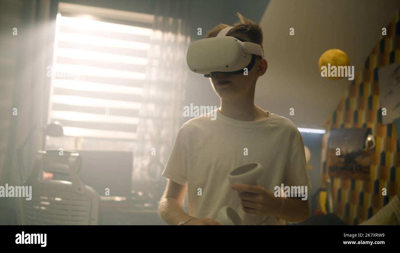Garçon très enthousiaste avec casque VR et manettes de jeu. Jeune ... Garçon très enthousiaste avec casque VR et manettes de jeu. Jeune ...