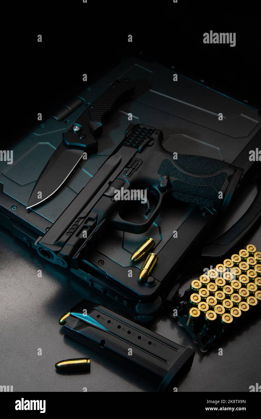 Un pistolet, des cartouches pour lui et un couteau pliant sur un fond sombre. Kit d'auto-défense ...