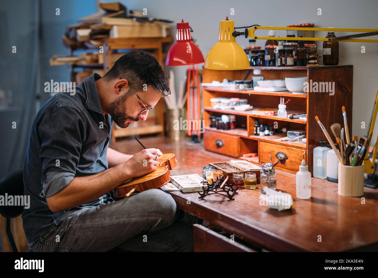 Vue latérale d'un artisan adulte en verres assis à une table en ...