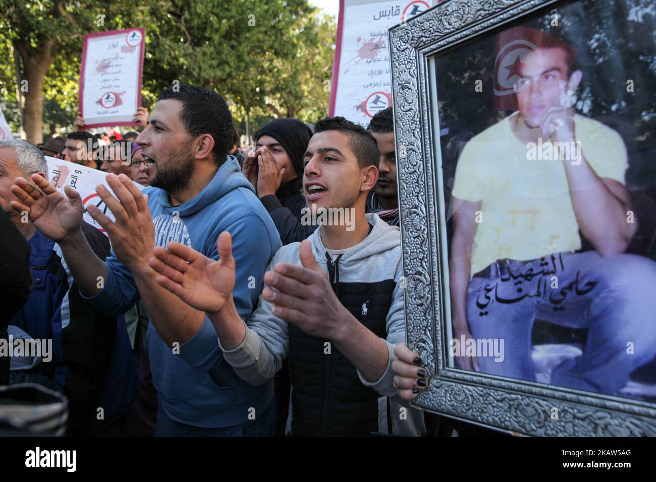 Les gens scandent des slogans tandis qu'un portrait d'un jeune homme ...