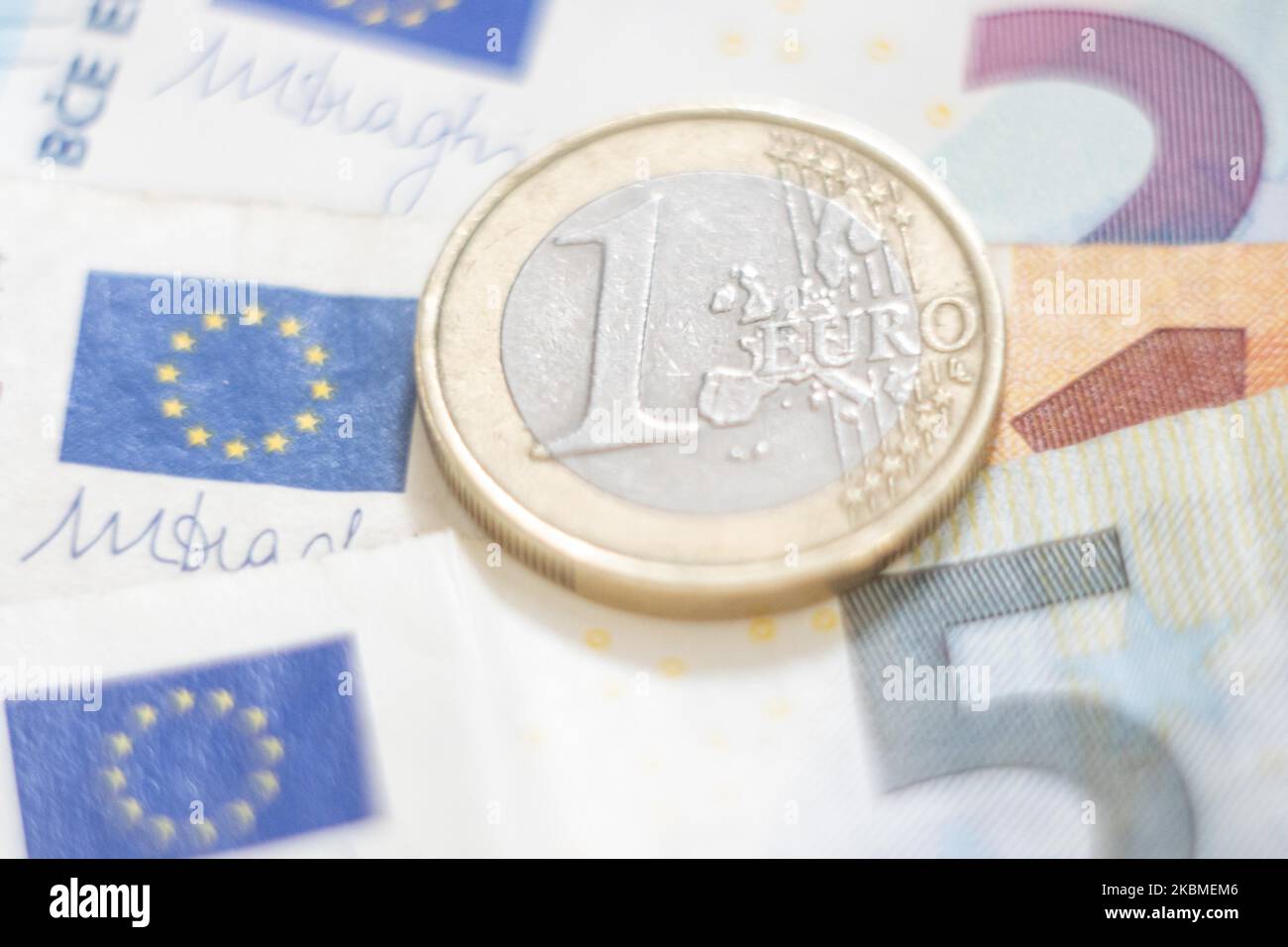 Une pièce en euros, empilée sur des pièces en euros et des billets en arrière-plan. Les pièces ...