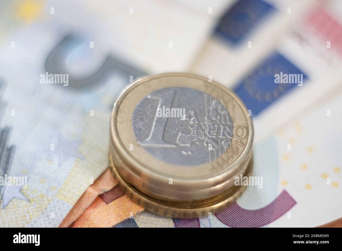 Une pièce en euros, empilée sur des pièces en euros et des billets en arrière-plan. Les pièces ...