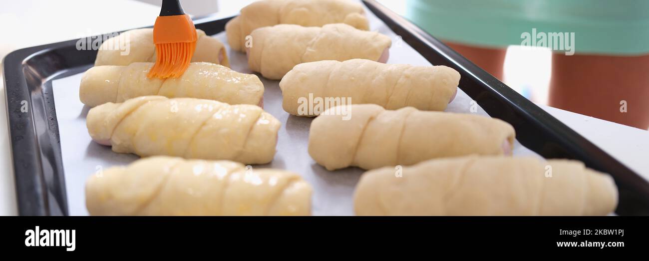 Femme prépare des croissants et badigeonnez la pâte avec du jaune d'œuf ...