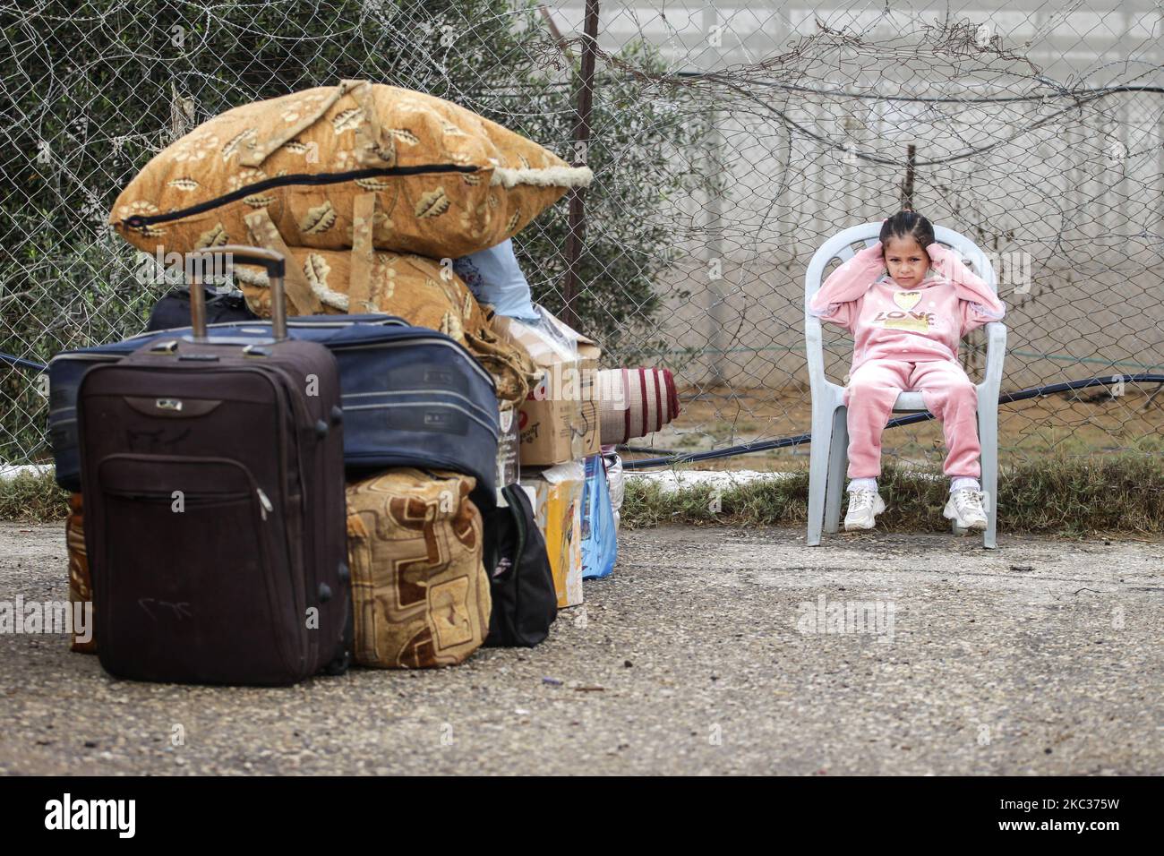 Une fillette palestinienne s'assoit à côté des bagages pendant qu'elle ...