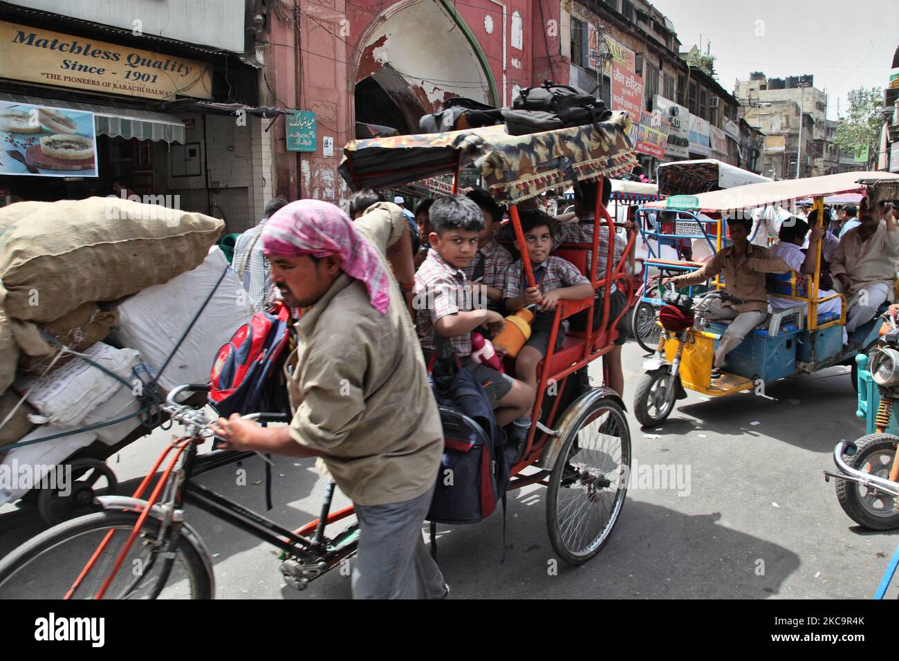 Les écoliers voyagent dans un pousse-pousse surchargé le long d'une rue ...