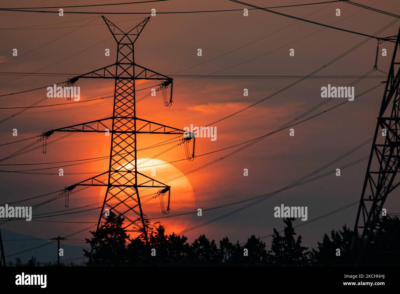 Coucher de soleil d'été en Grèce avec pylônes électriques près de la ville de Thessalonique ...